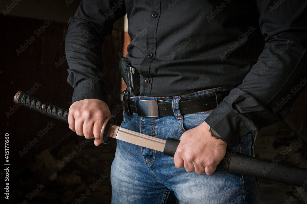 a special police officer holds a pistol, a sword and a grenade in his ...