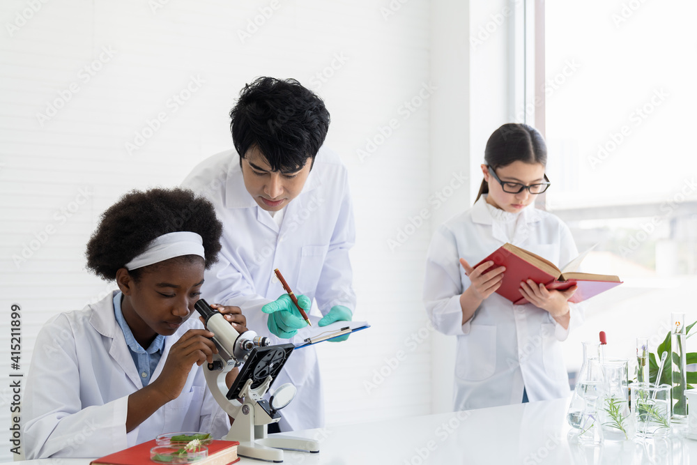 Asian teacher and diverse student doing tests of plants in classroom ...