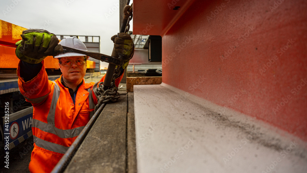 Male Driver Wearing Full PPE Chaining Down a load of Steel onto a ...