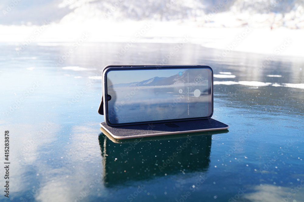 Сотовый телефон стоит открытый для съемки на ровном гладком льду Stock ...