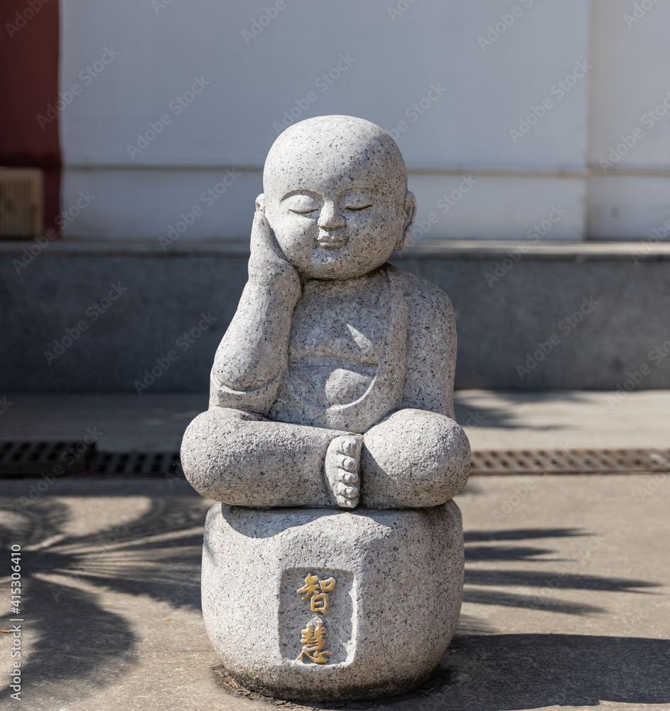 Stone figurine of sitting little monk thinking and meditating in ...