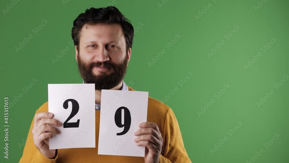 Man holding number 29 sign. Cheerful white bearded good-looking man in ...