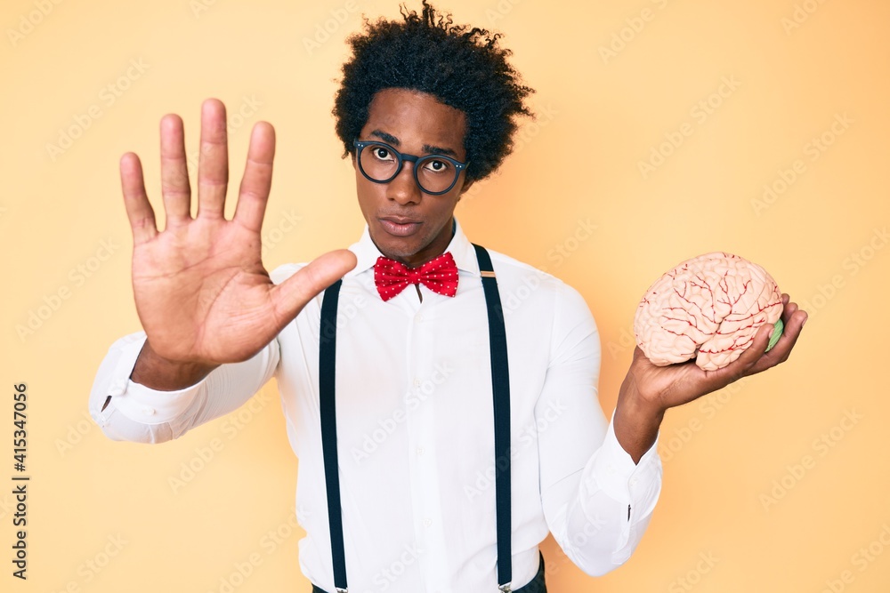 Handsome african american nerd man with afro hair holding brain with ...
