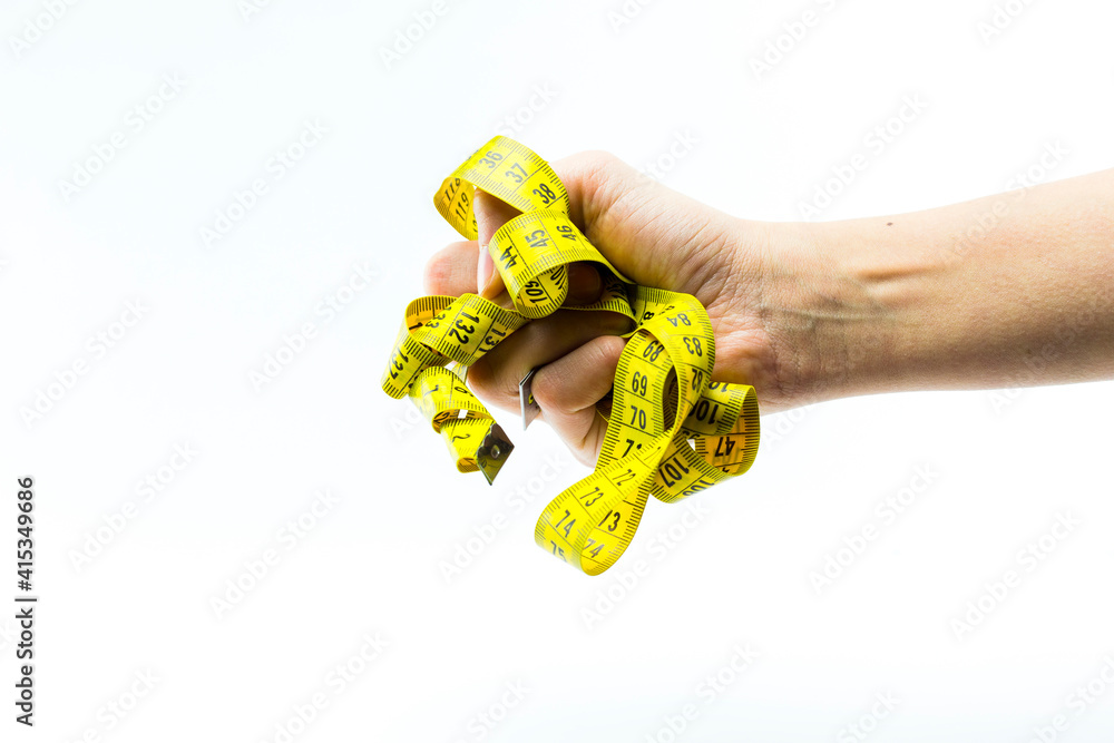 hand with clenched fist squeezing a yellow measuring tape with numbers ...