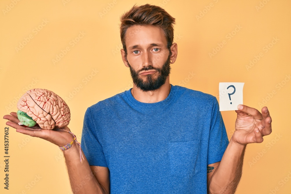 Handsome caucasian man with beard holding brain and question mark ...