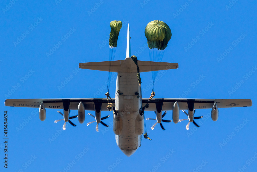 Military parachutist paratroopers jumping from a US Marines C-130 ...