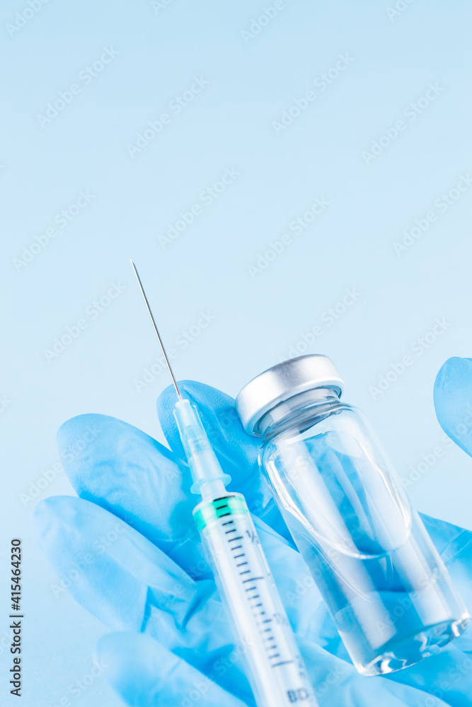 Vaccine vial and syringe in doctor hand. Doctor's hand in surgical ...