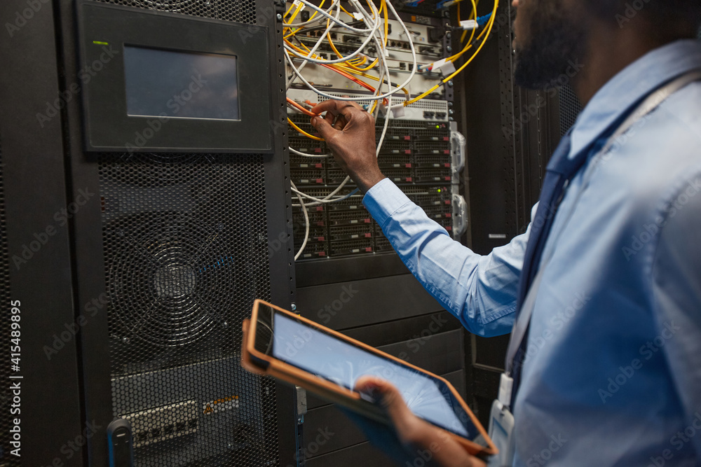 Cropper portrait of African American network engineer connecting cables ...