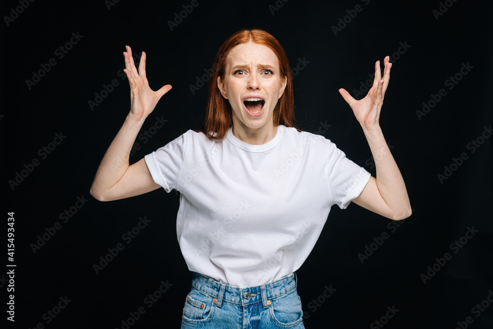 Terrified young woman wearing T-shirt and denim pants shouting with ...