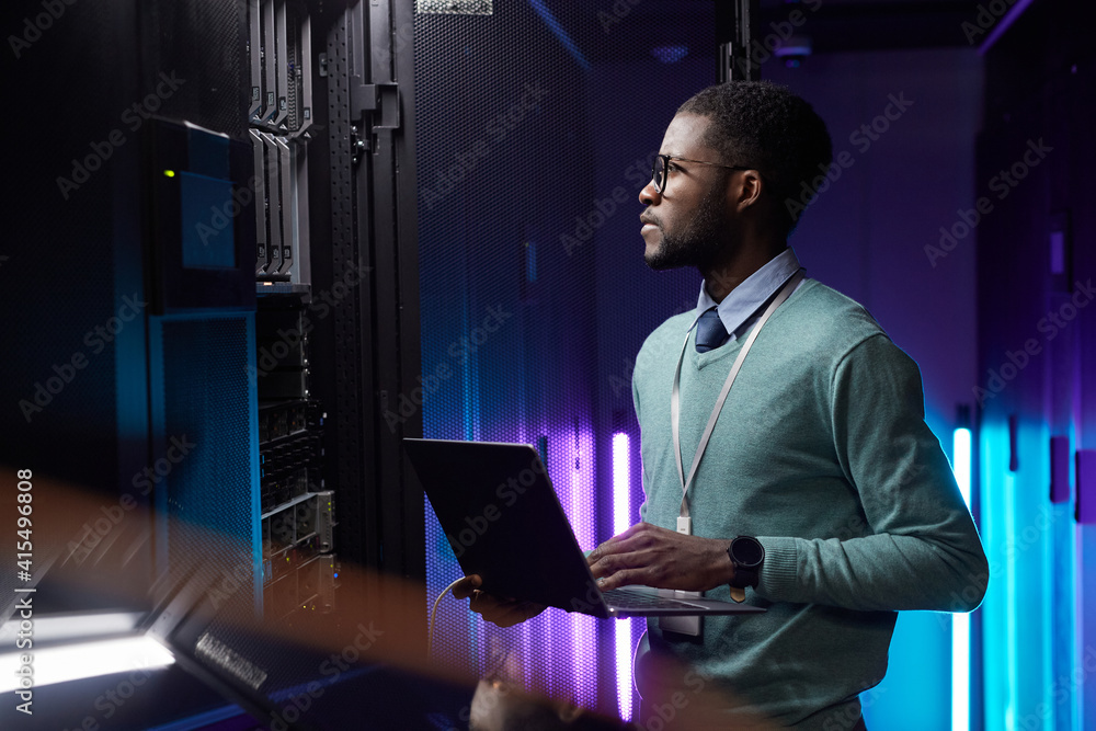 Side view portrait of African American data engineer holding laptop ...