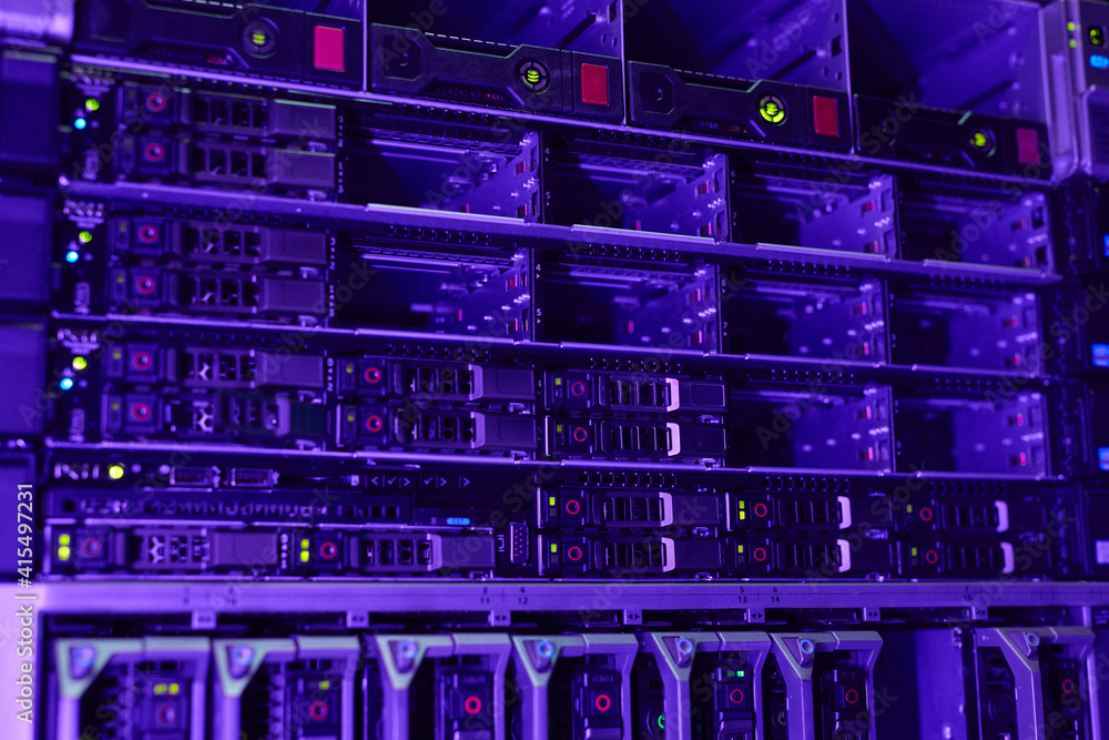 Futuristic background image of rack servers in supercomputer network lit by blue and violet ...