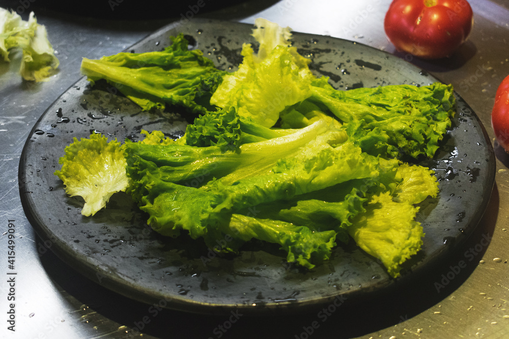 Lechuga fresca cortada sobre un plato de barro y alrededor dos tomates ...
