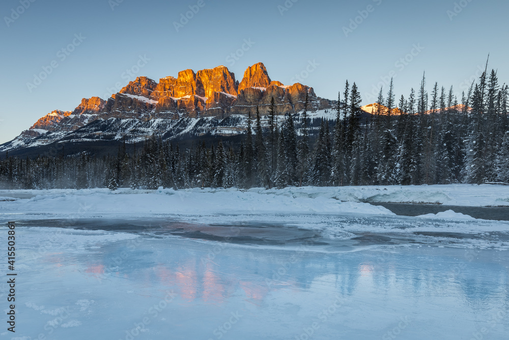 Calm Canadian Rockies winter landscape at sunset of a cold river with ...