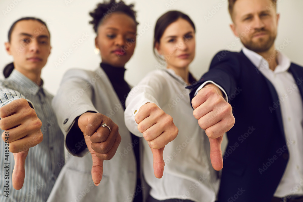 Group of young diverse people giving thumbs down, hands in closeup ...