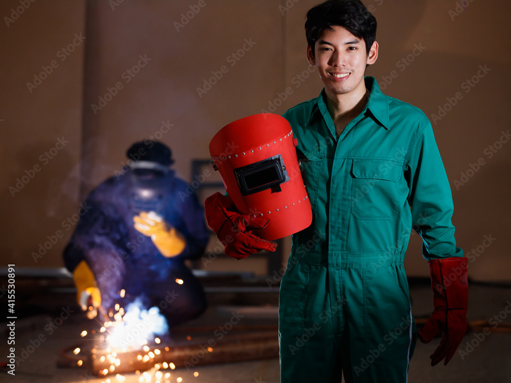 smart confident young Asian man wearing a factory uniform holding a ...