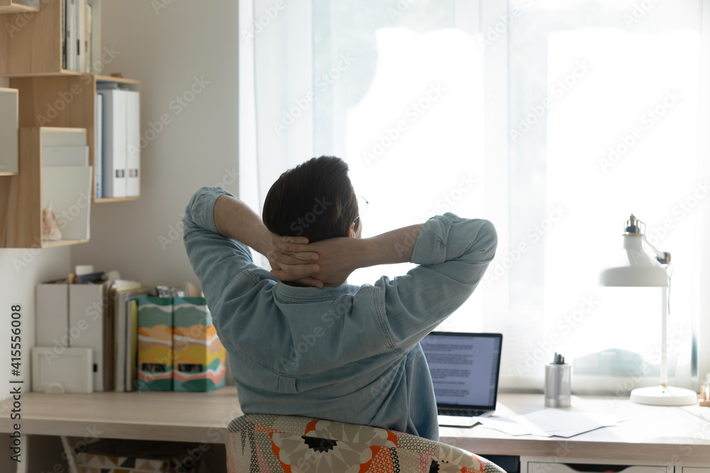 Back view of man sit at desk at home office distracted from computer ...