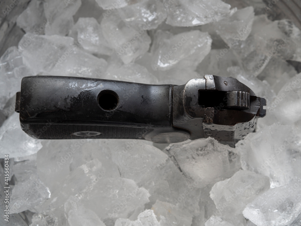 Police 9mm pistol (gun) frozen in a bucket with crushed ice cubes. The ...