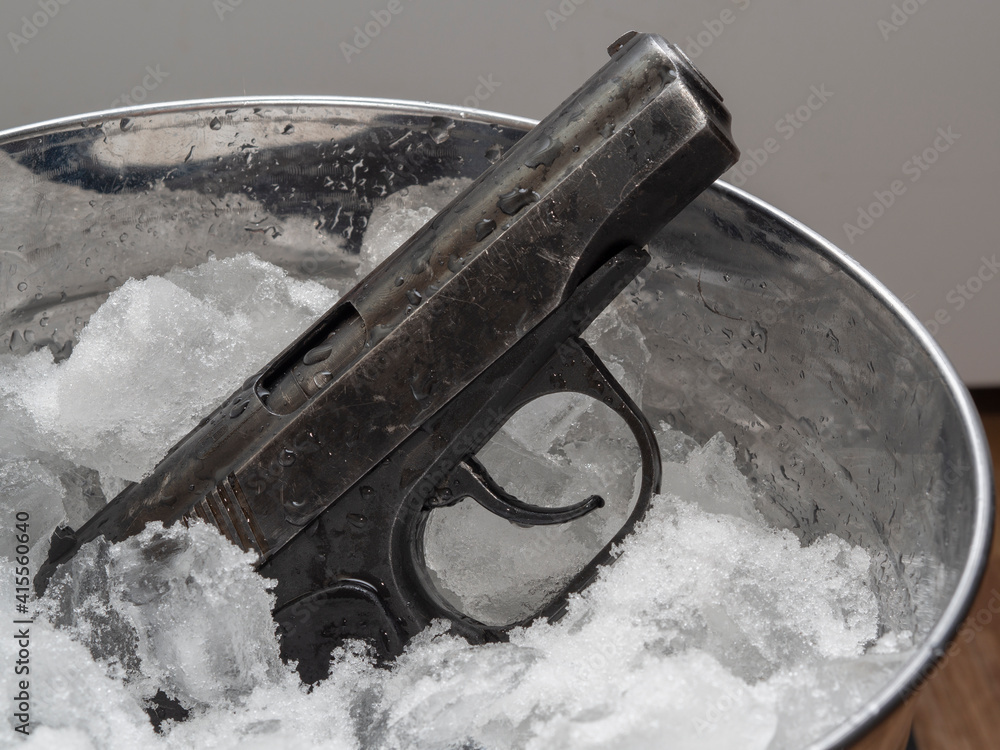 Police 9mm pistol (gun) frozen in a bucket with crushed ice cubes. The ...