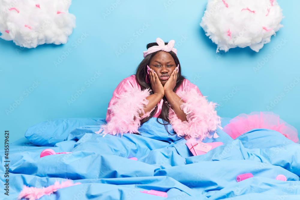 Sad bored dark skinned Afro American woman keeps hands on cheeks feels ...