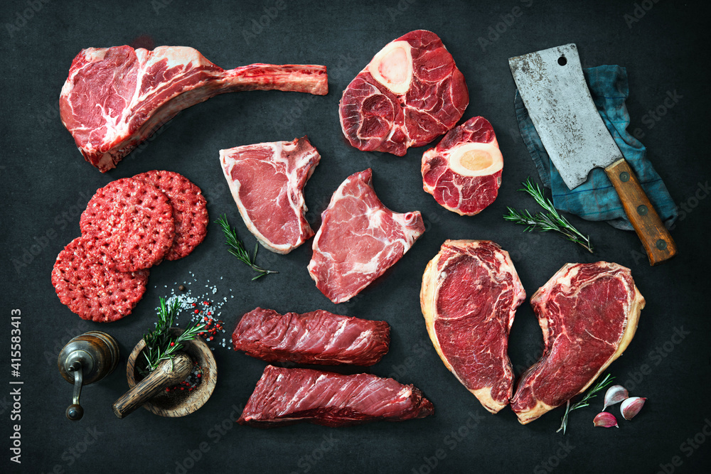 Variety of raw cuts of meat, dry aged beef steaks and hamburger patties ...