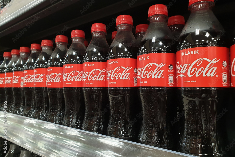 Rows of Coca-Cola bottle drink on display in a grocery store. Coca-Cola ...