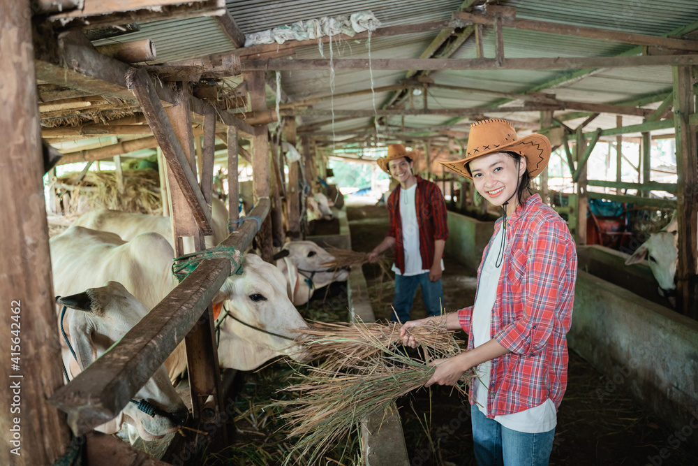 farmer girl wearing a hat smiling to the camera while holding straw ...