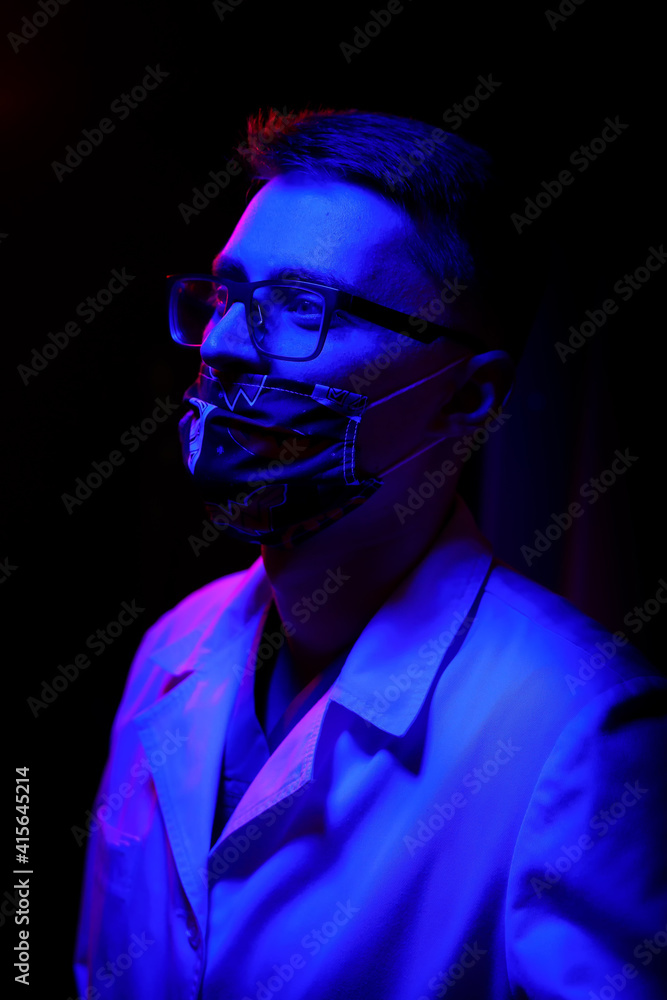 Head and shoulders portrait of a man in scrubs and facial mask. Medic ...