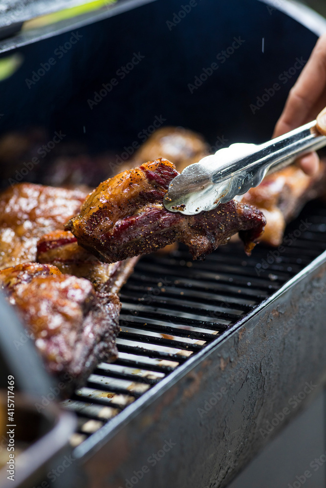 Smoke rising around a slow cooked beef brisket on the grill grates of a ...