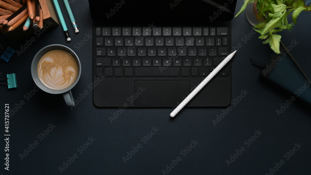 Overhead shot of wireless keyboard, stylus pen, coffee cup and plant on ...