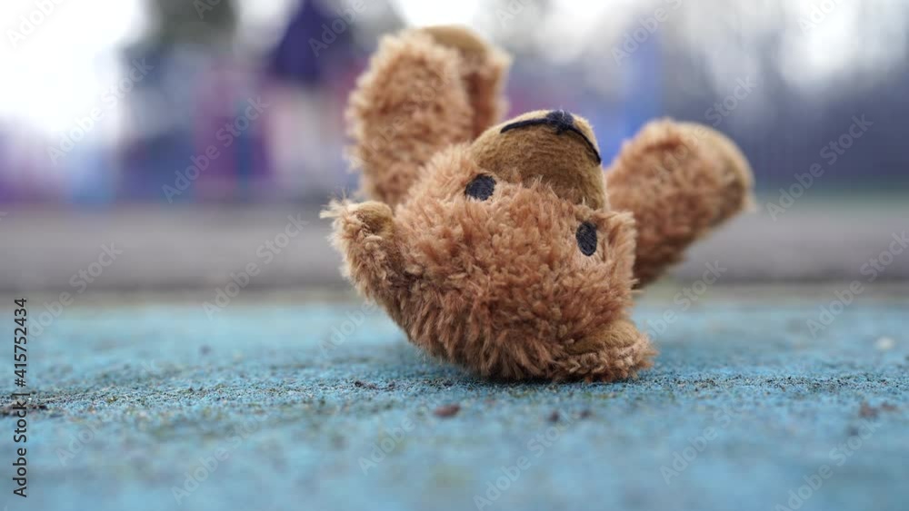 Vidéo Stock Lonely Teddy bear with sad face lying on footpath with ...