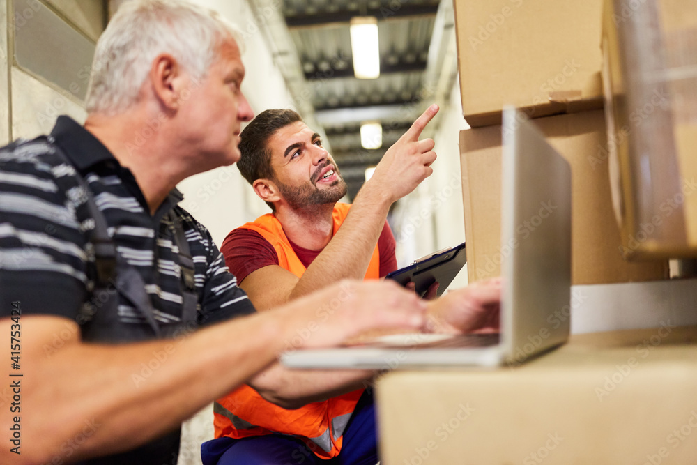 Two warehouse workers at laptop pc with packages Stock Photo | Adobe Stock