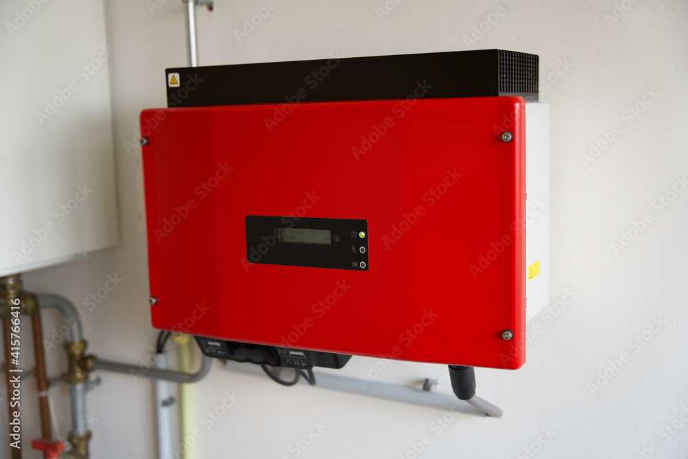 red solar power inverter mounted on a white wall. Sustainable energy ...