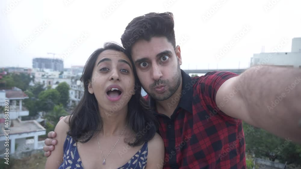 Joyful girl and guy taking funny selfie,having fun making funny faces ...