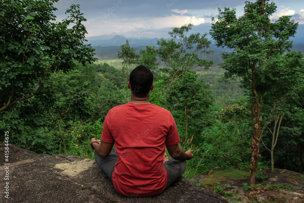 man meditating at rock in deep green forests for spiritual ...