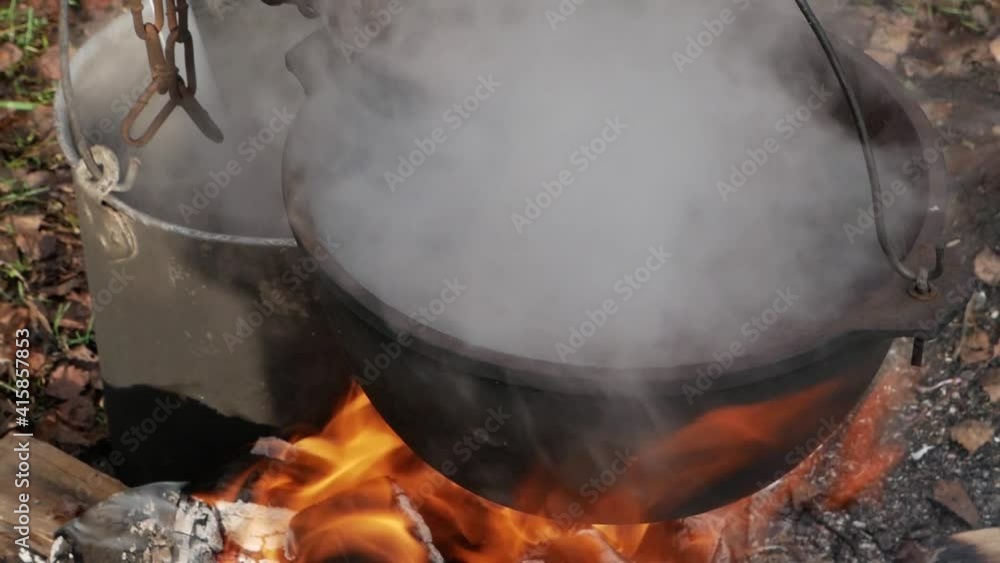 Cooking in a metal pot over a fire. Cooking over a fire in two metal ...