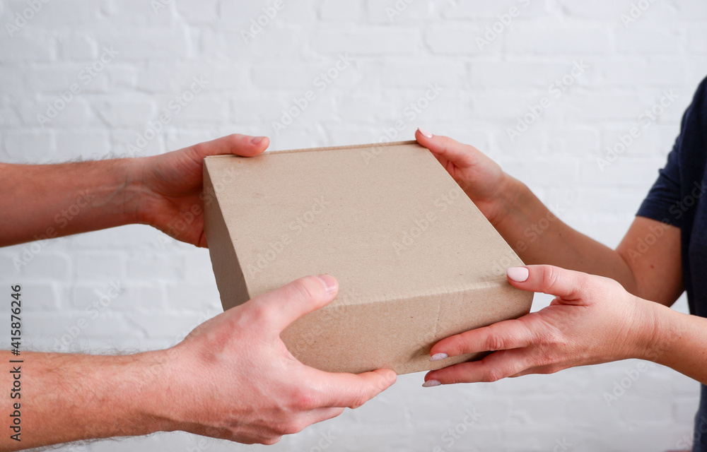 Delivery. Man courier hands over cardboard boxes to woman. Close-up on ...