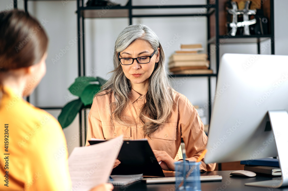 Friendly female mature hr manager listening and looks a resume of a new ...