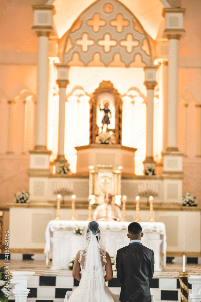 A couple face the priest at the altar, at a typical Catholic church ...
