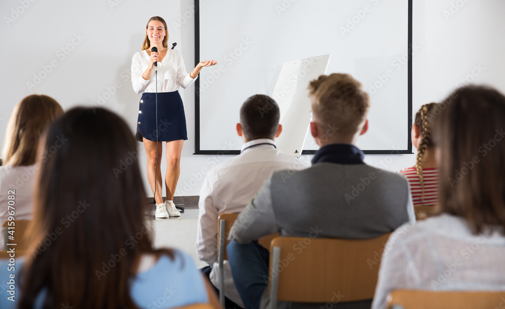 Friendly female teacher lecturing to attentive adult students at ...