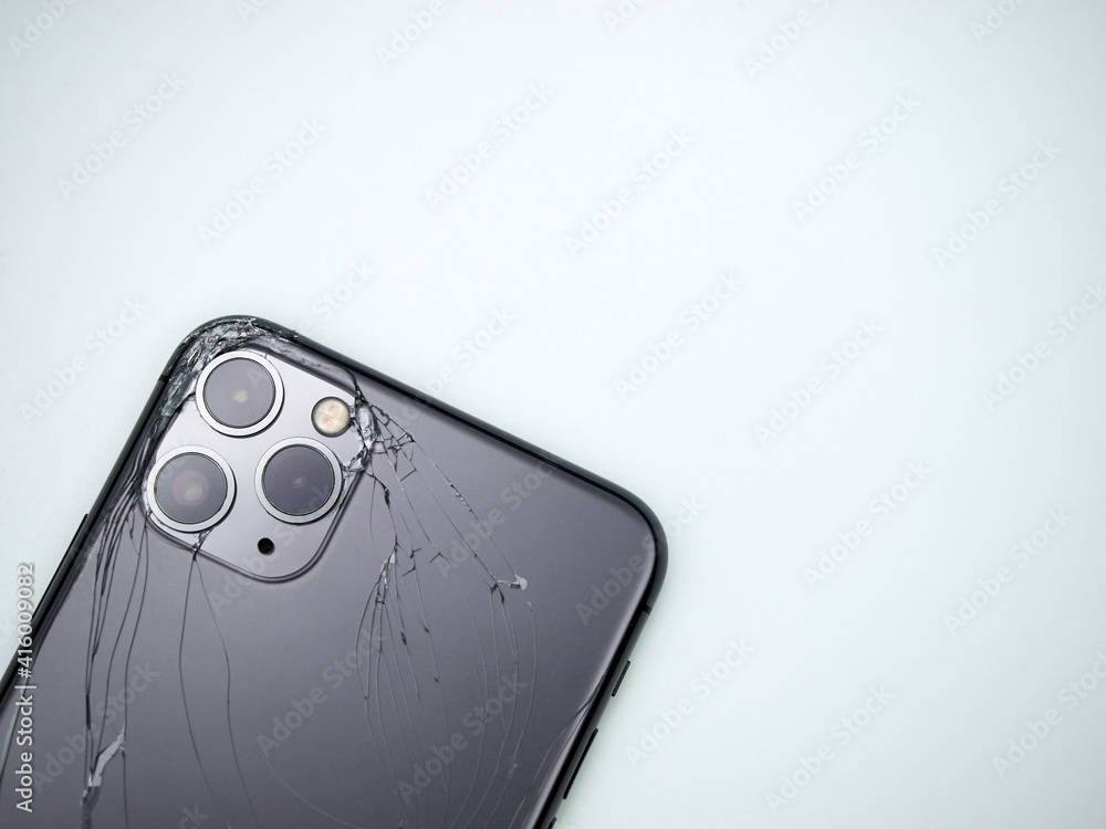 The back of the space grey modern smartphone has broken glass on white ...