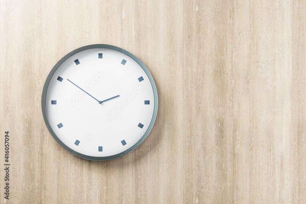 White round wall clock in metal frame on blank wooden wall with space ...