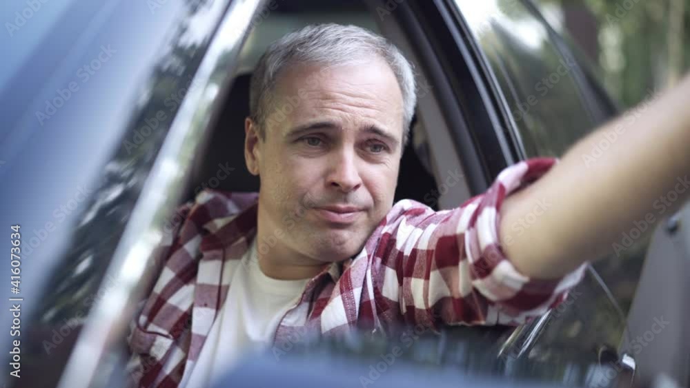 Portrait of angry man talking and gesturing out of side window sitting ...