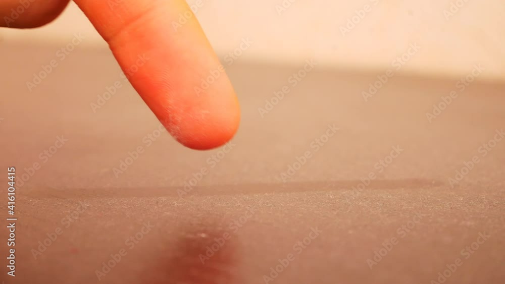 Close-up of a man's finger sliding across the dusty surface of ...
