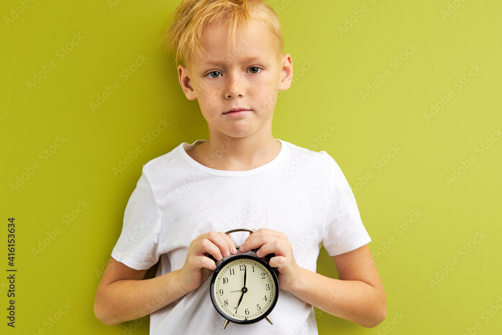 serious kid boy holding black alarm clock. childhood and time ...