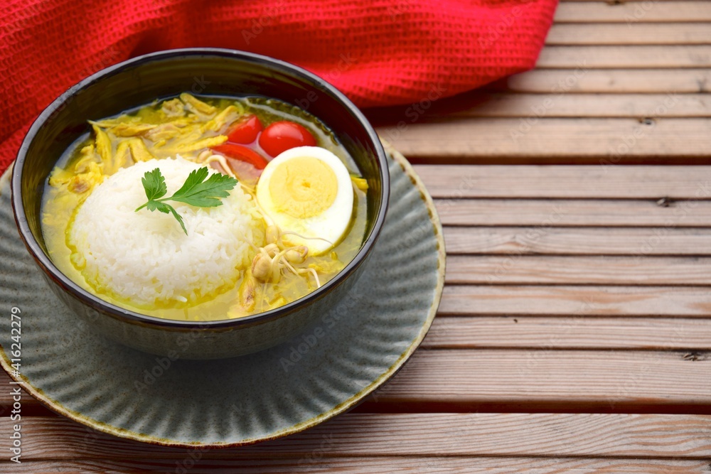 Soto Ayam, yellow spicy chicken soup with egg, tomato, bean sprouts and ...