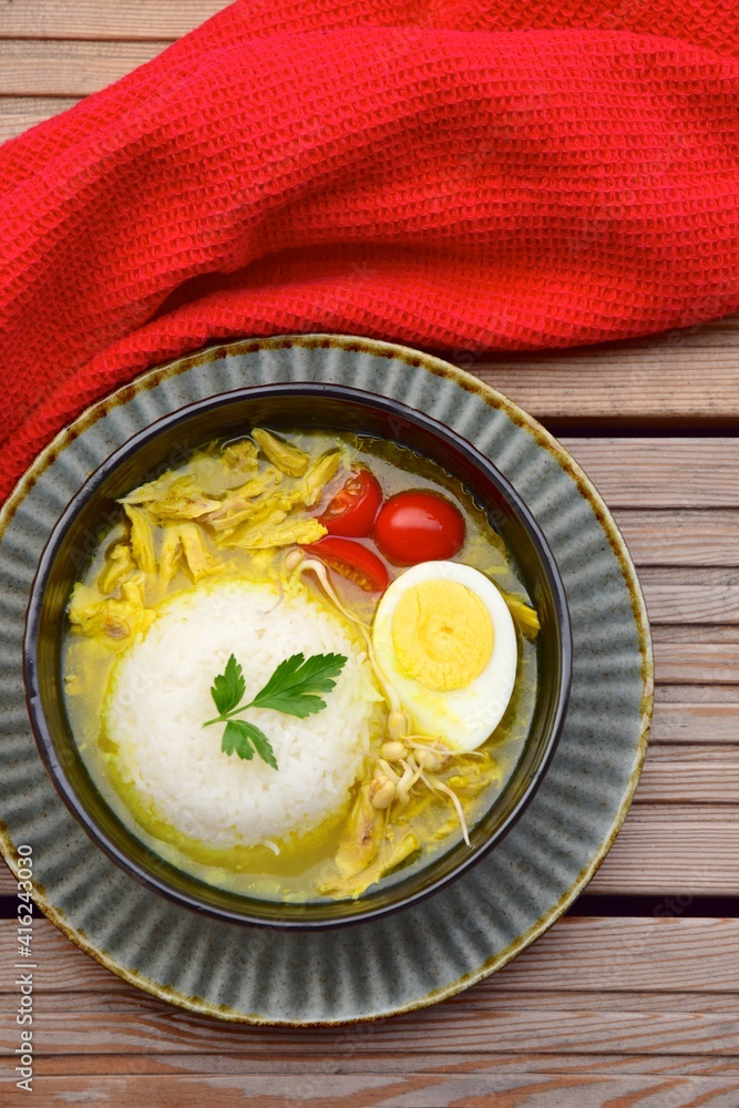 Soto Ayam, yellow spicy chicken soup with egg, tomato, bean sprouts and ...