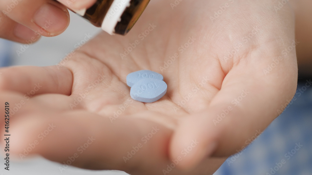 Two big blue diamond-shaped pills labeled 100 fall into palm of hand ...
