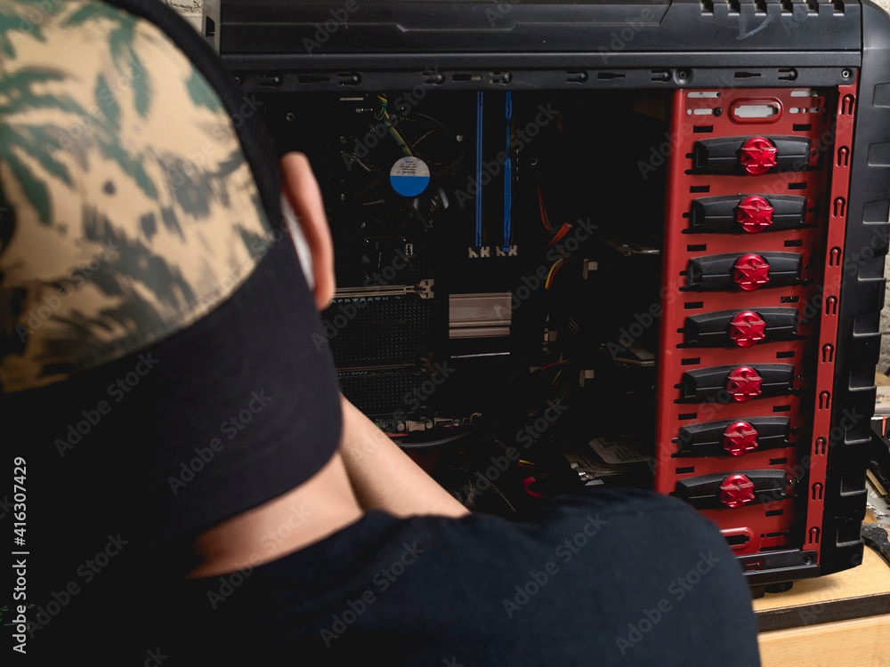 A computer technician wearing a baseball cap opens up a red desktop ...