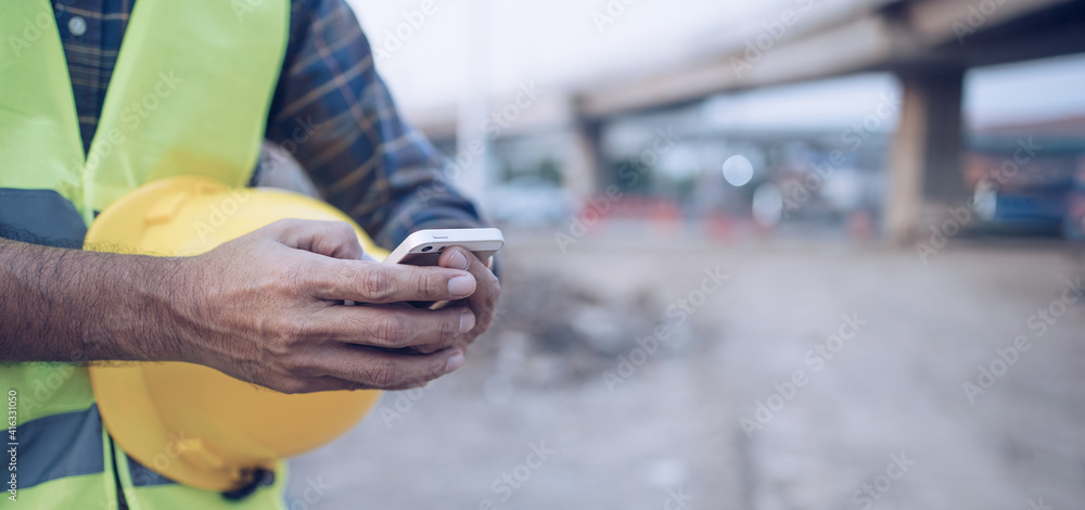 construction working on his smartphone at the construction site with ...