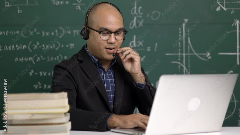 Indian young teacher man sitting wearing headset teaching online video ...